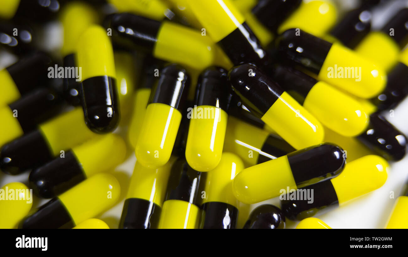 Close up of many black and yellow pills and tablets medicine isolated ...