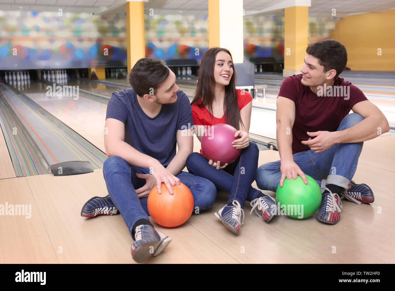 Friends sitting on floor in bowling club Stock Photo - Alamy