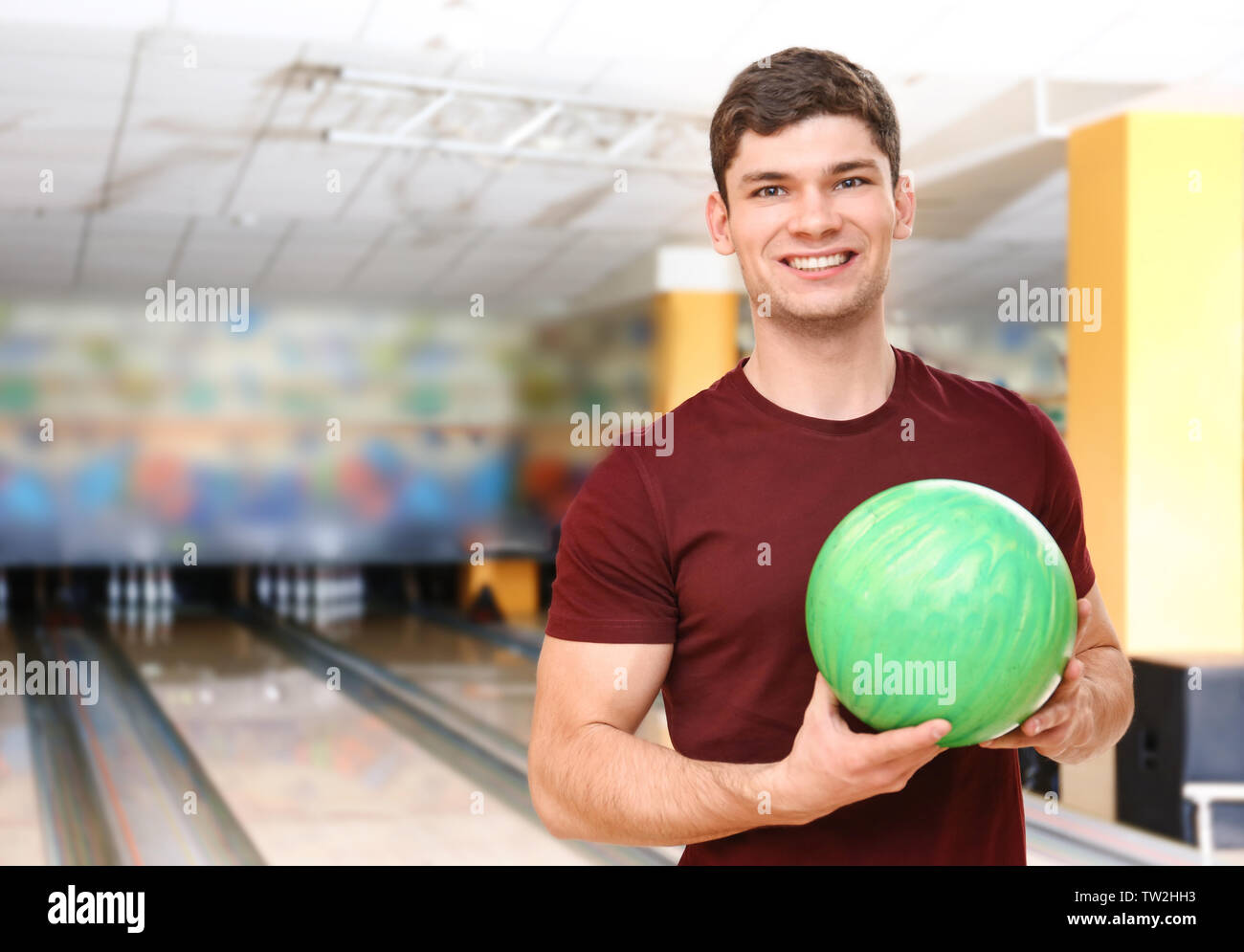 Handsome young man with ball in bowling club Stock Photo - Alamy
