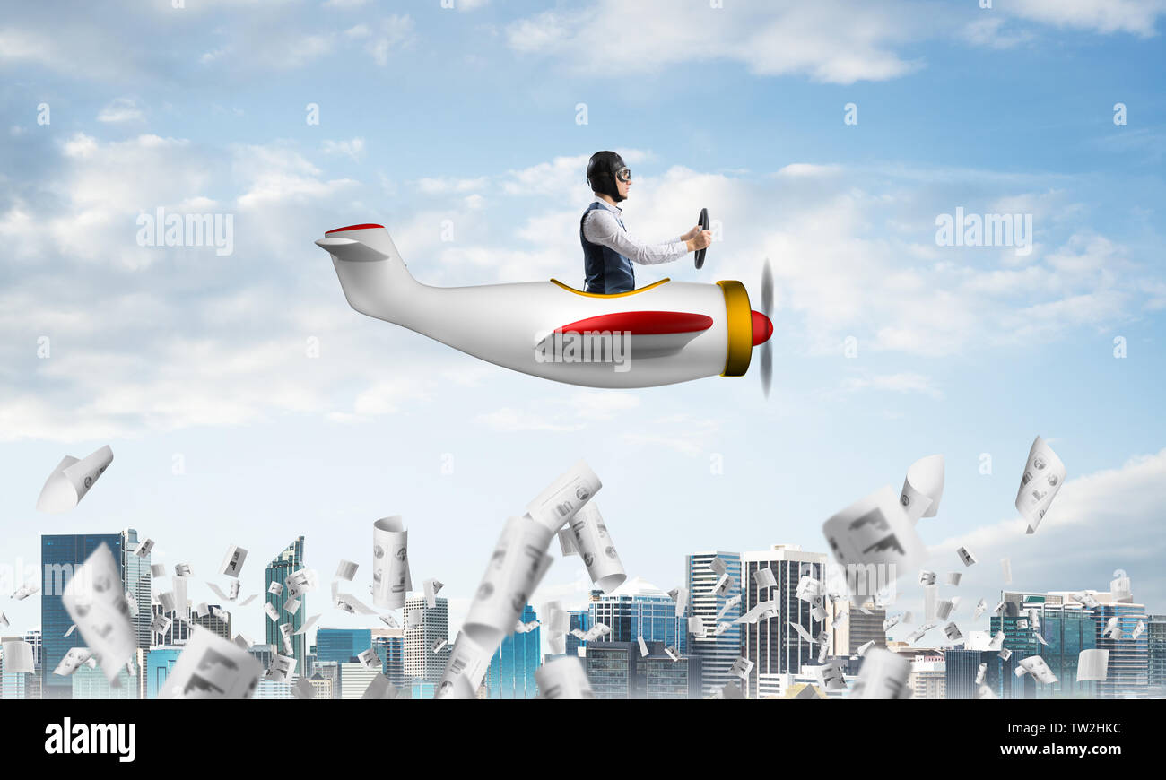 Businessman in aviator hat and goggles driving propeller plane above ...