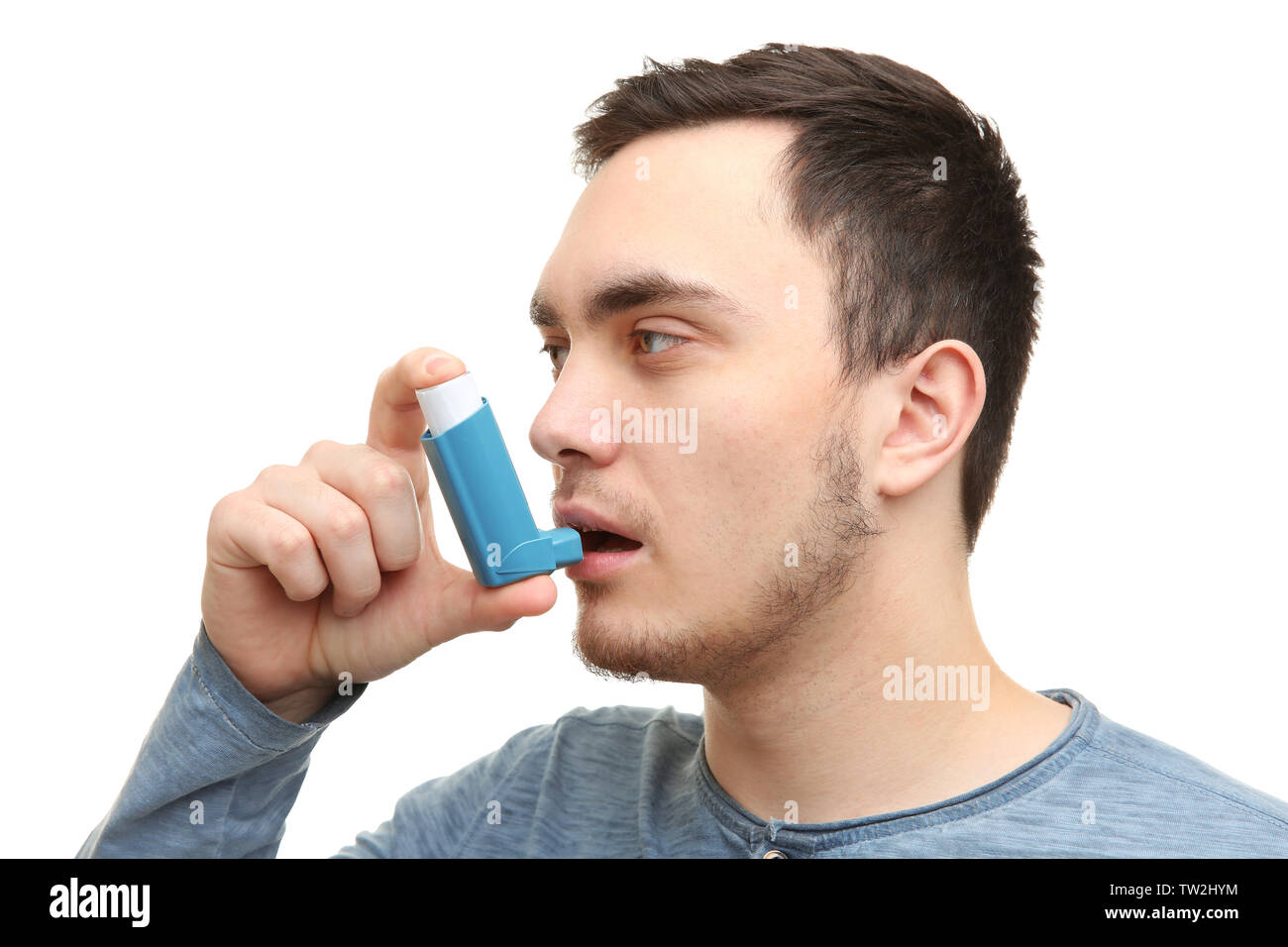 Young man using inhaler during asthmatic attack, on white background ...