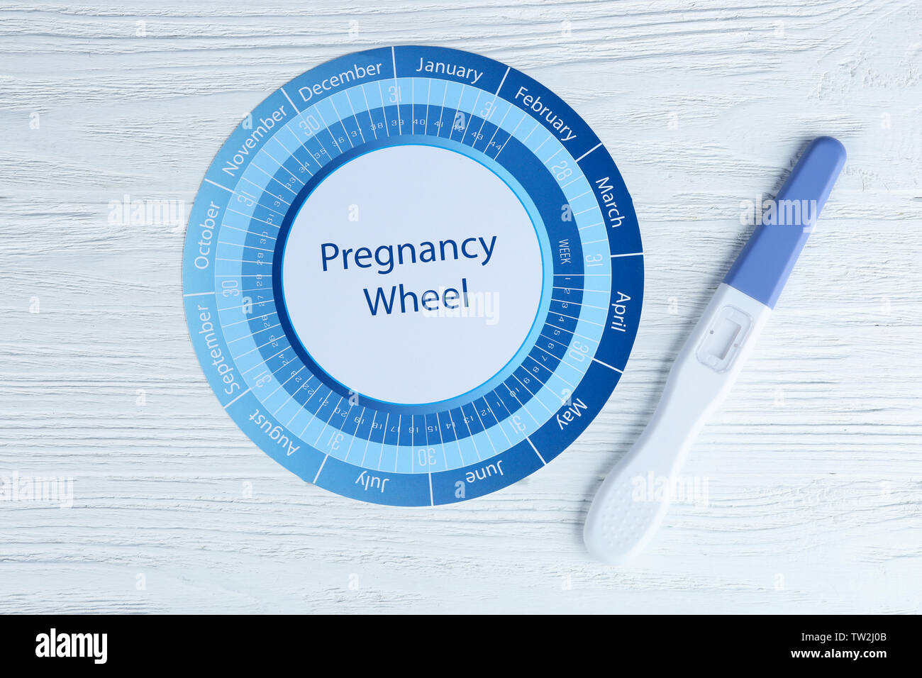 Pregnancy wheel calendar and test on white wooden table Stock Photo - Alamy