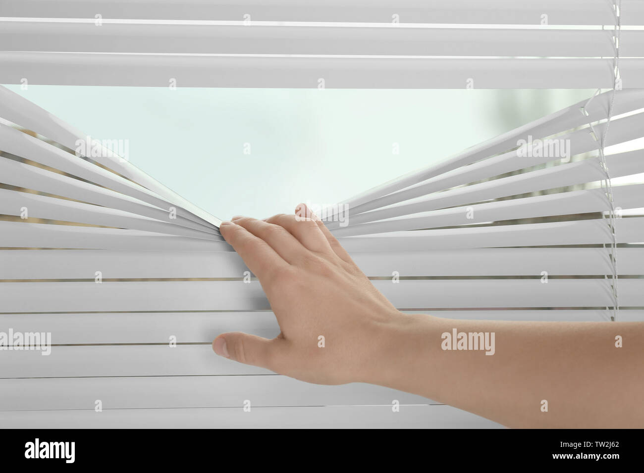 Female hand separating slats of blinds to see through window Stock ...