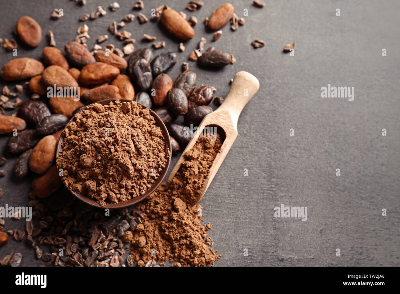 Bowl and wooden scoop with aromatic cocoa powder on gray background ...