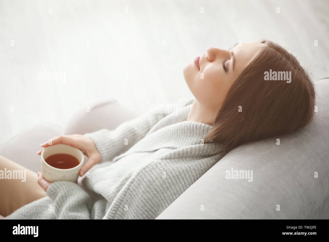 Beautiful young woman drinking tea while resting at home Stock Photo ...