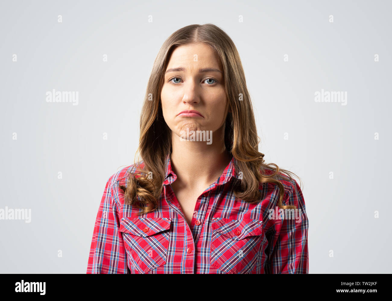 Unhappy young woman looking at camera. Emotional brown haired woman has ...