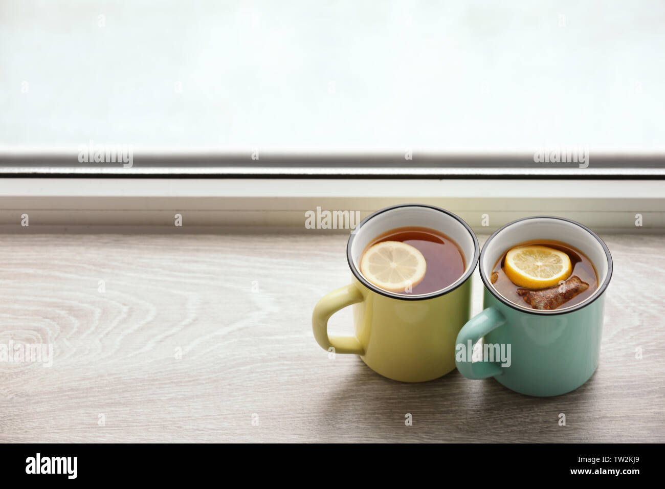 Cups of hot tea with lemon on window sill Stock Photo - Alamy