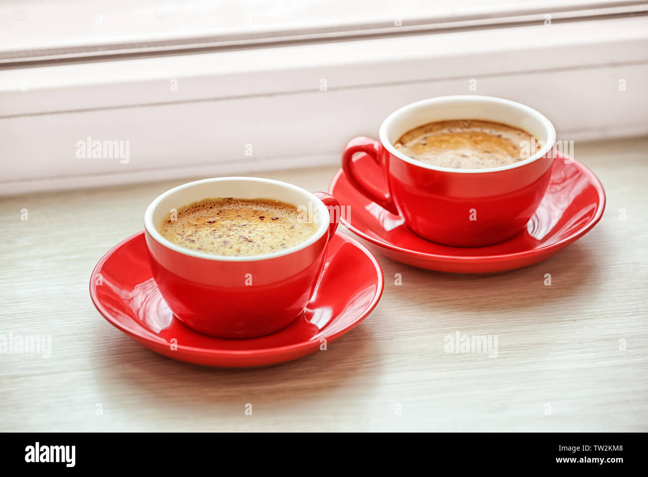 Cups with hot coffee on window sill Stock Photo - Alamy