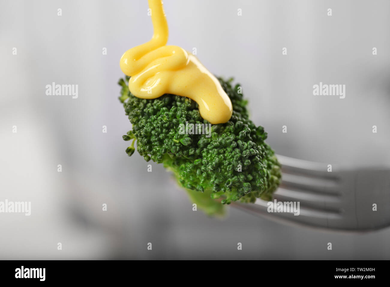 Fork with broccoli and pouring cheese sauce on blurred background Stock ...