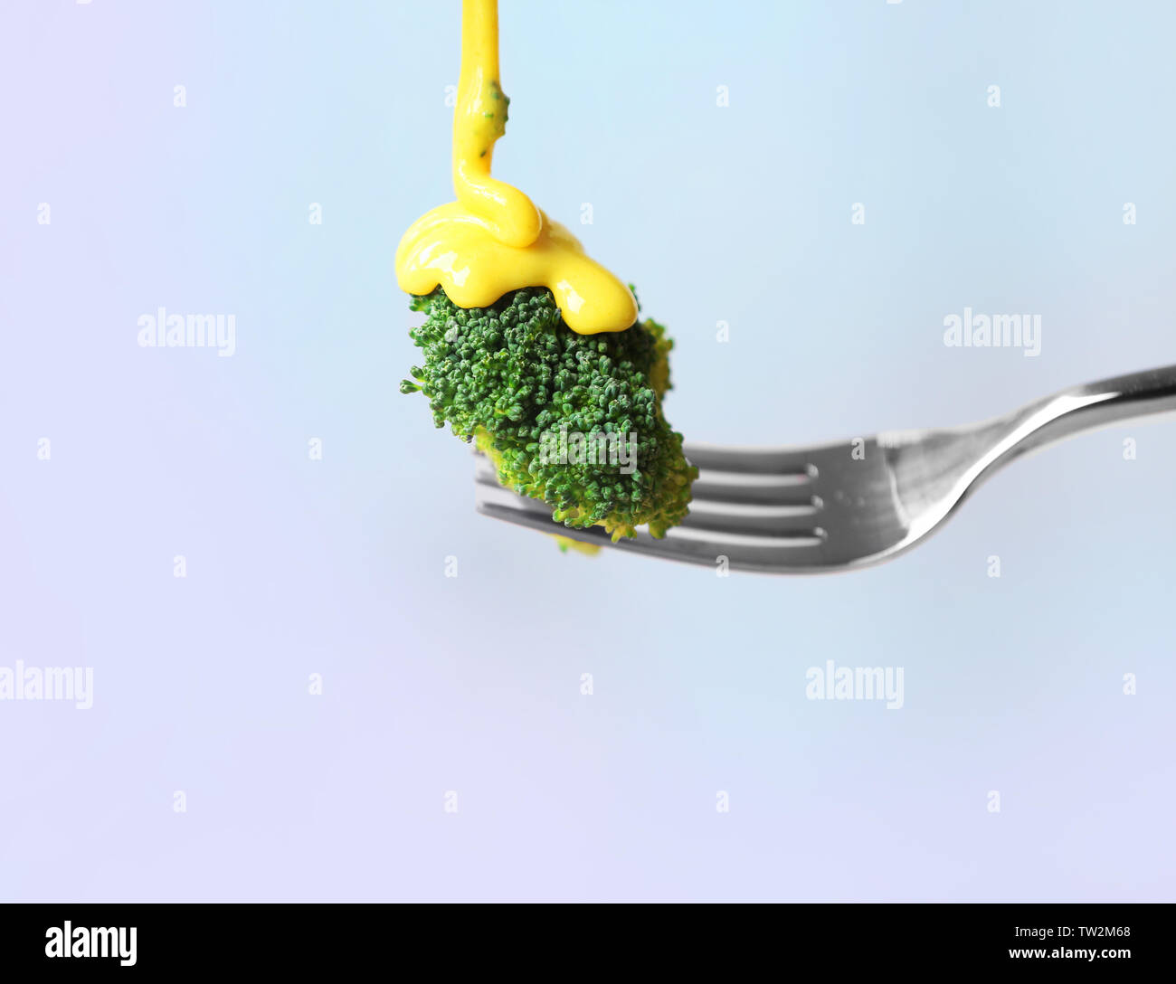 Fork with broccoli and pouring cheese sauce on blurred background Stock ...