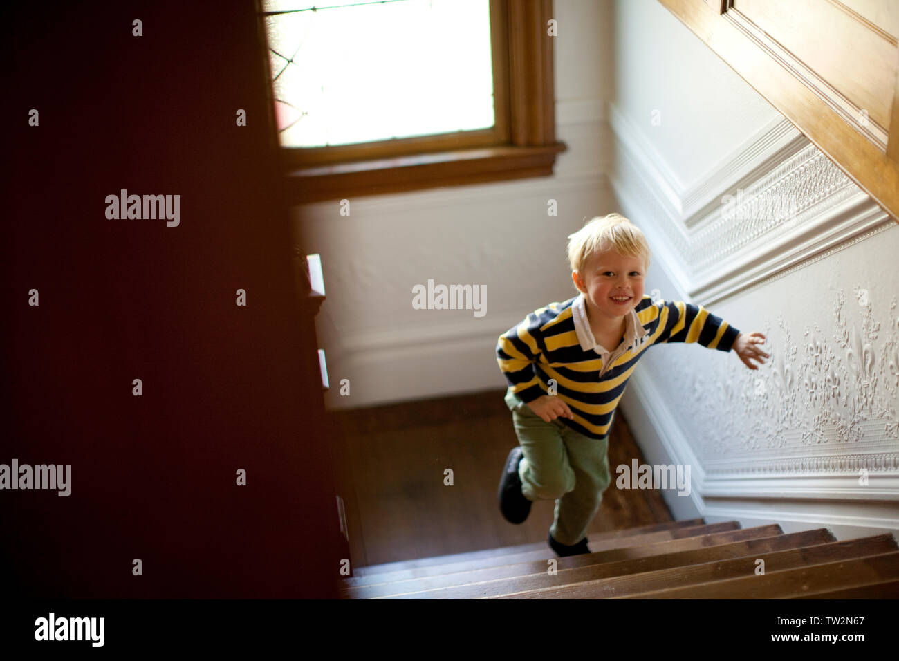 Little boy walking up staircase Stock Photo - Alamy