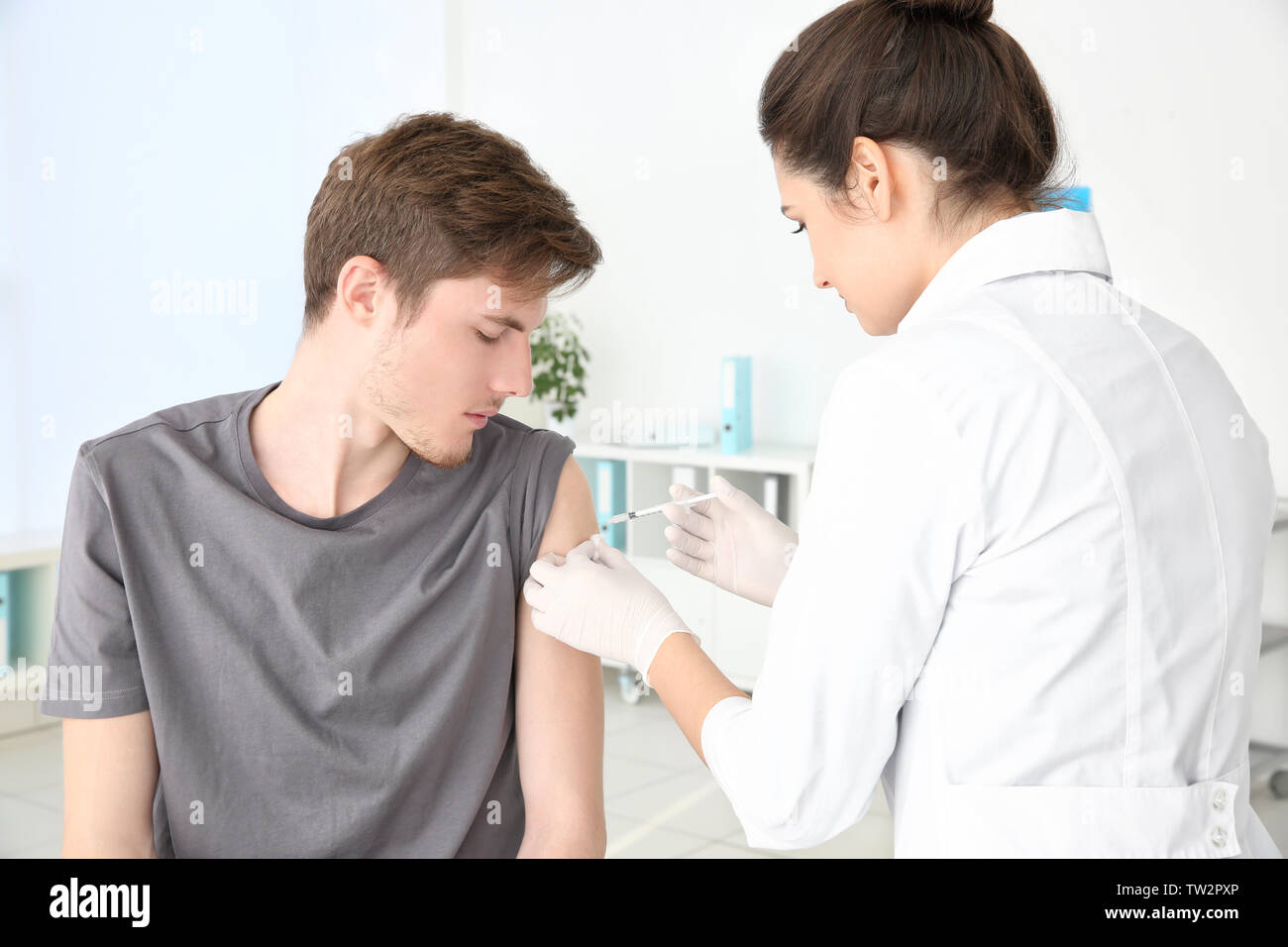 Young man receiving injection from medical assistant in clinic Stock ...