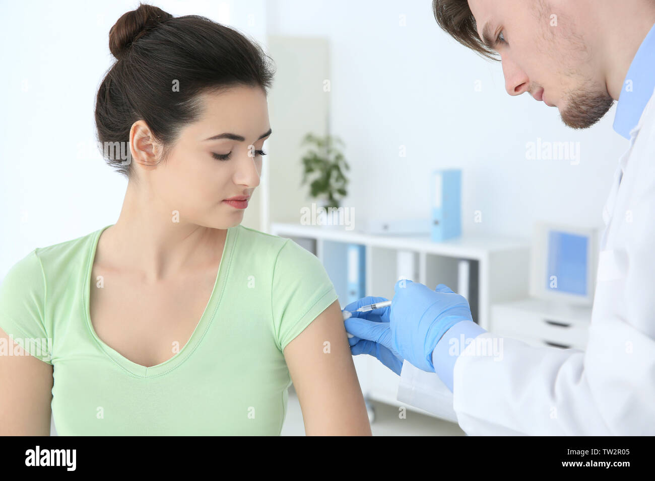 Young woman receiving injection from medical assistant in clinic Stock ...