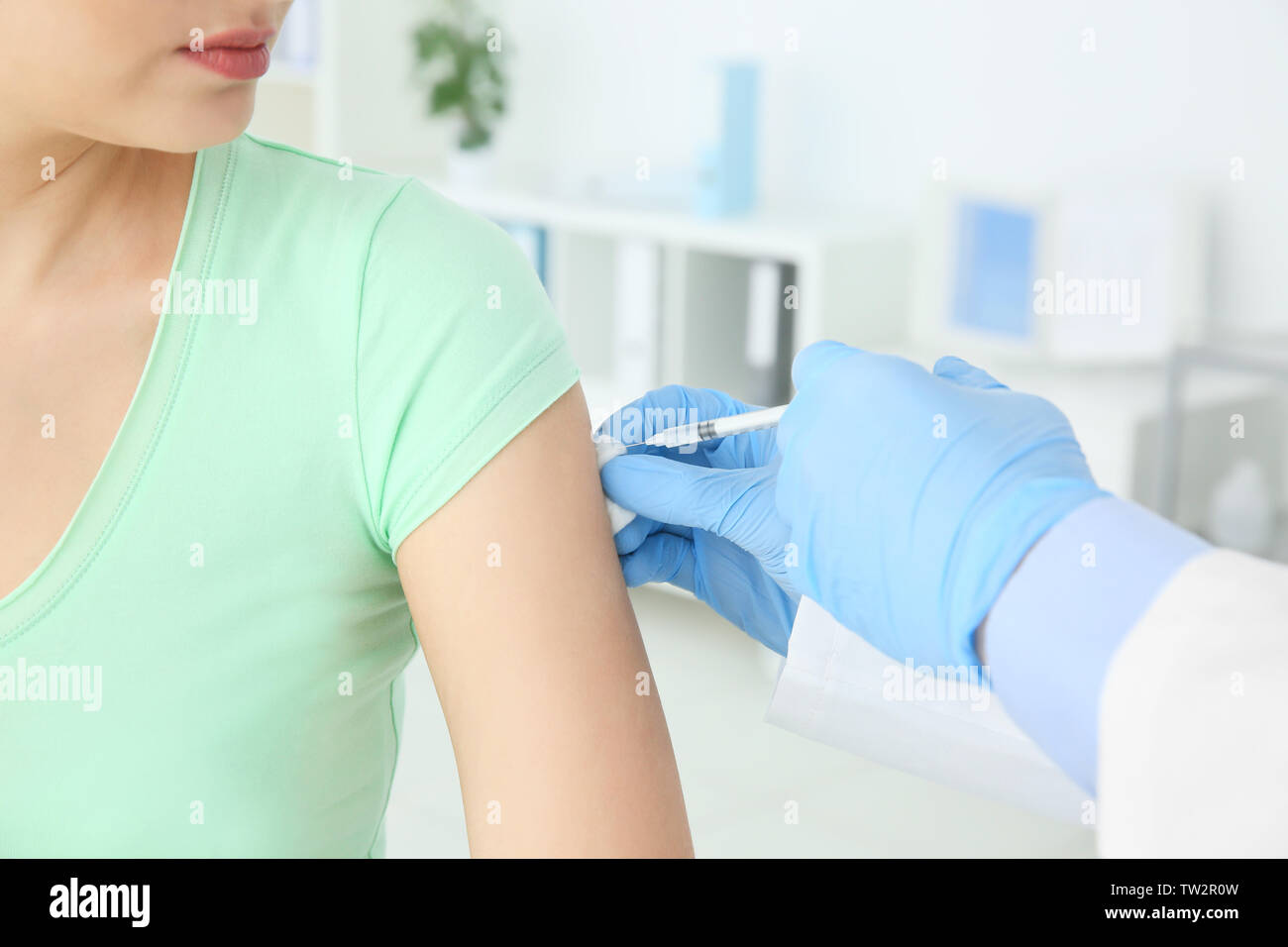 Young woman receiving injection from medical assistant in clinic ...