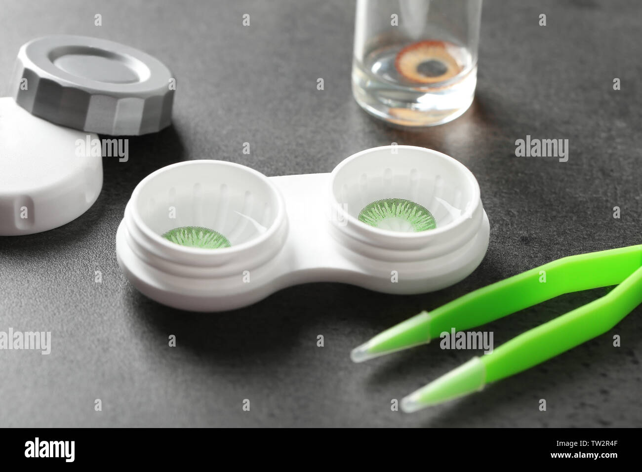 Container with contact lenses and tweezers on gray table Stock Photo ...