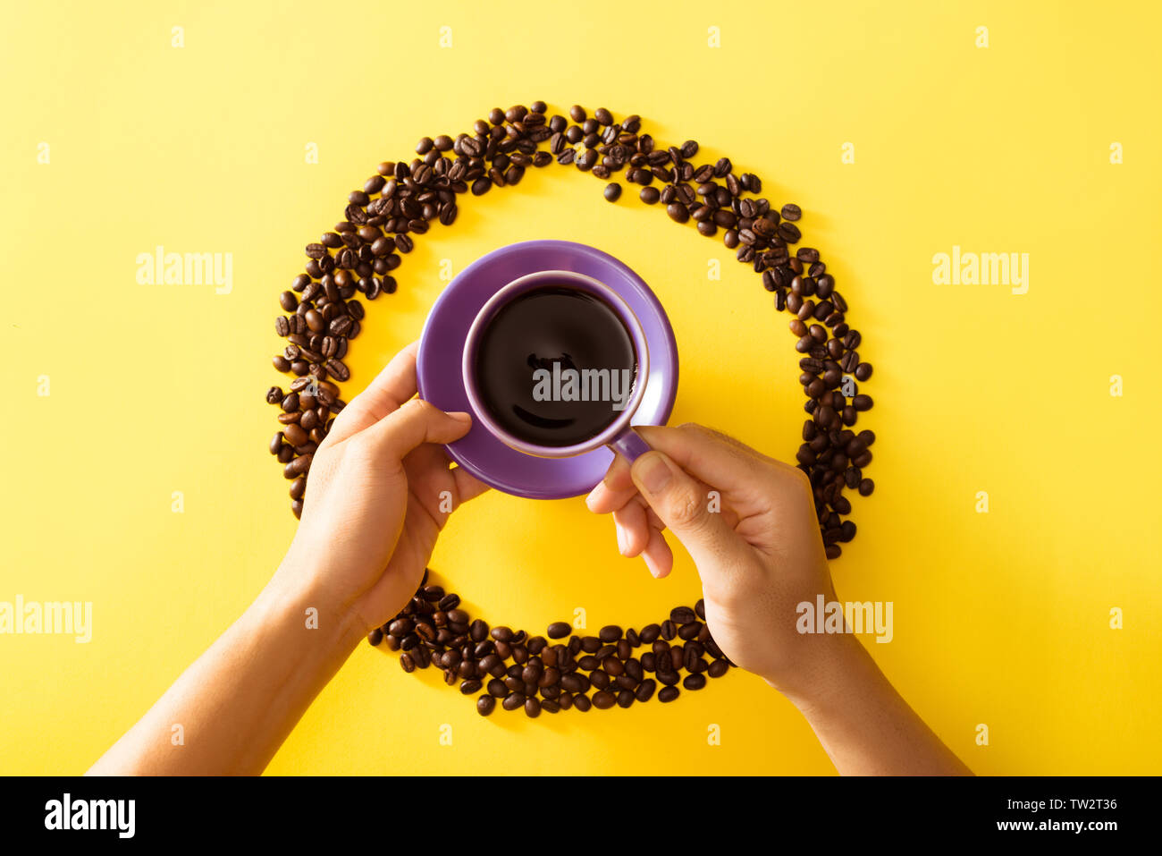 Hand holding cup of coffee on the yellow background Stock Photo - Alamy
