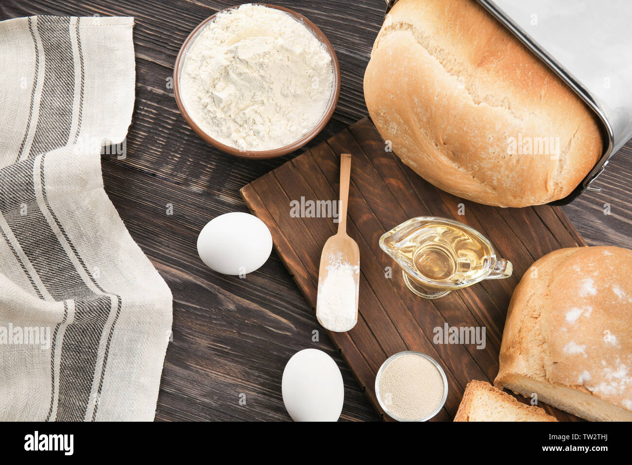 Loaf in bread machine pan and ingredients on wooden table Stock Photo ...