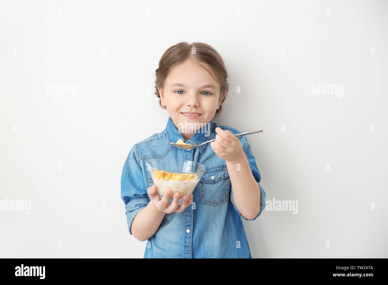 Cute little girl eating cornflakes on white background Stock Photo - Alamy