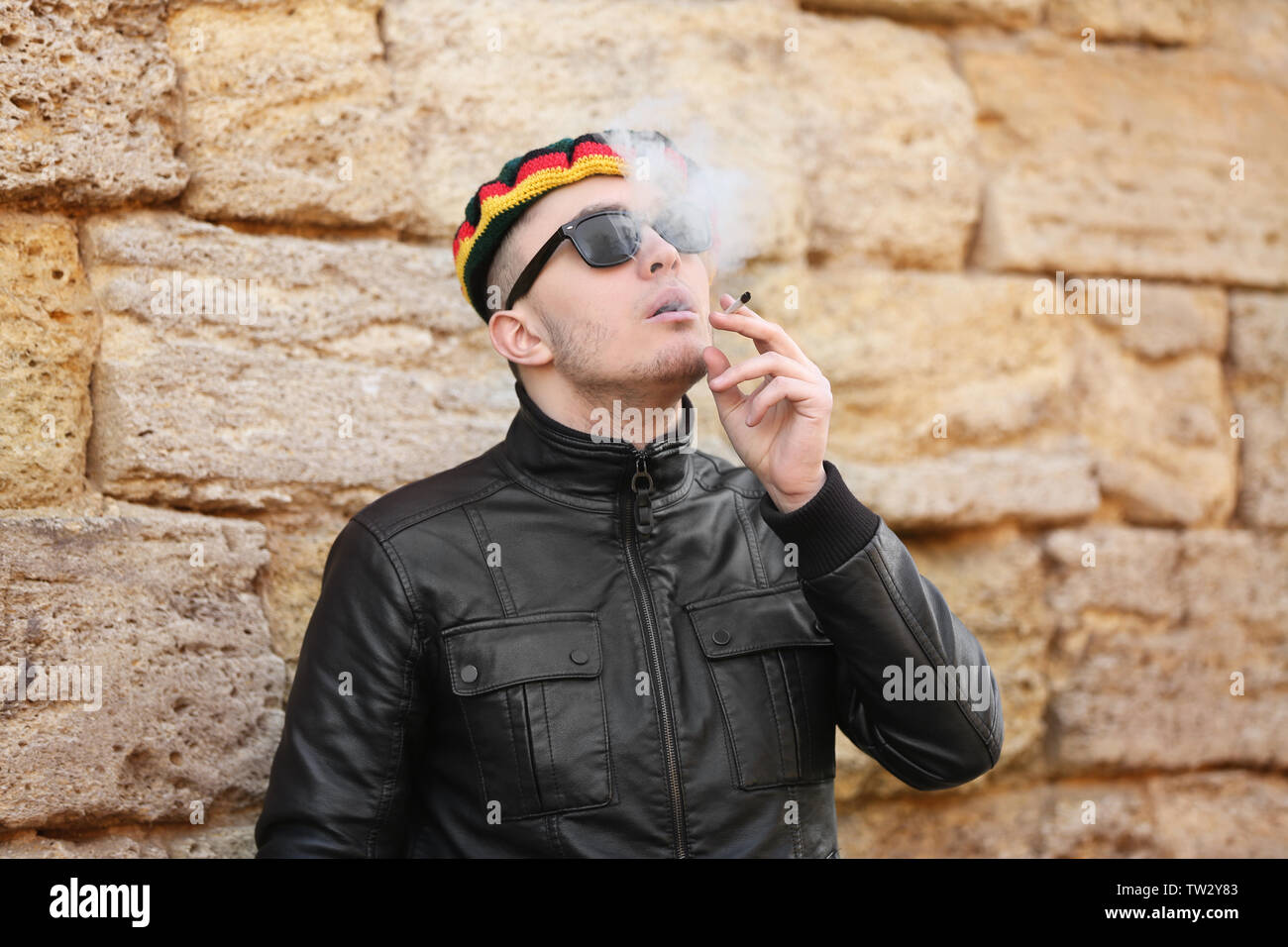 Handsome young man smoking weed outdoors Stock Photo - Alamy