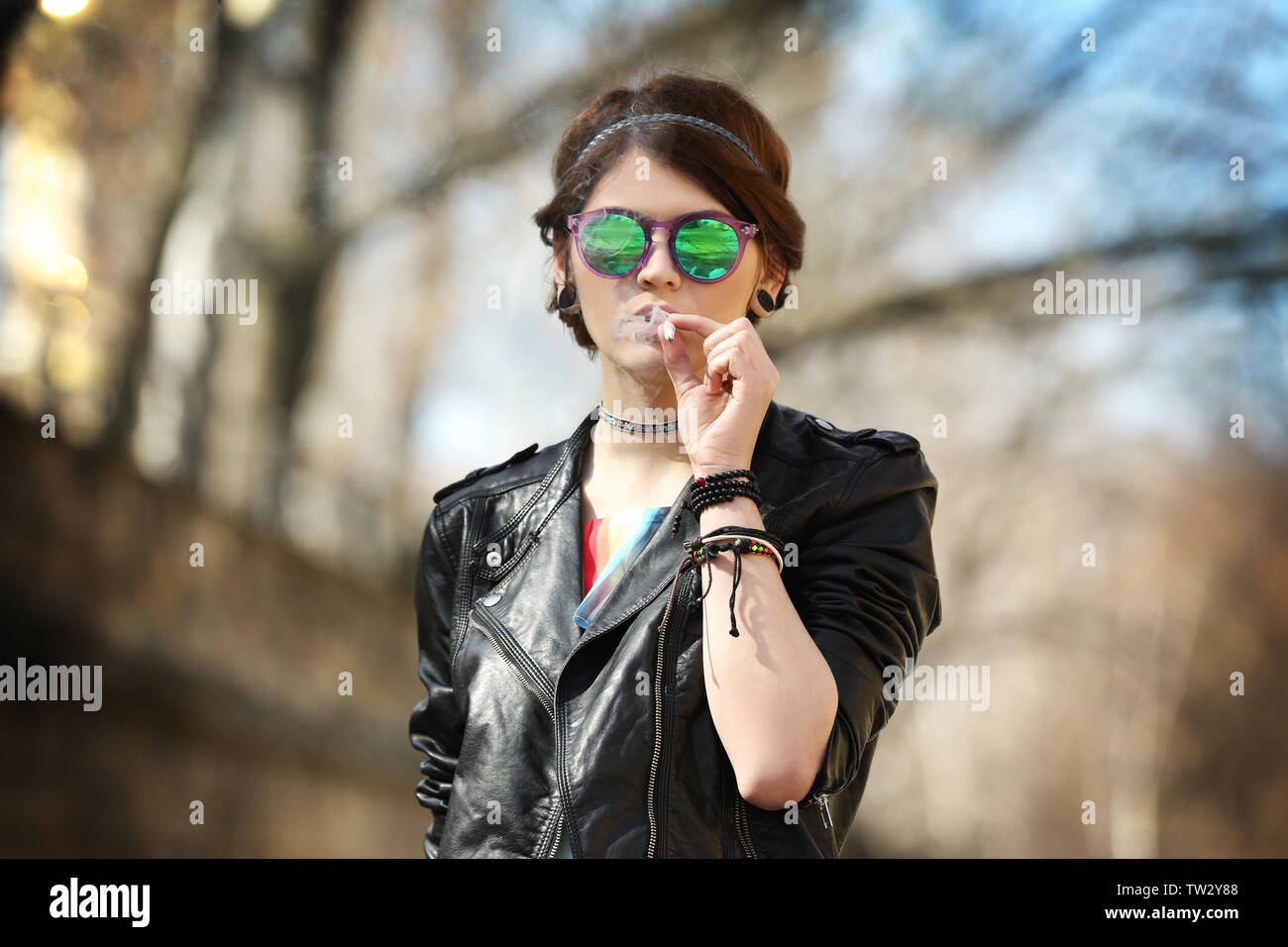 Beautiful young woman smoking weed outdoors Stock Photo - Alamy