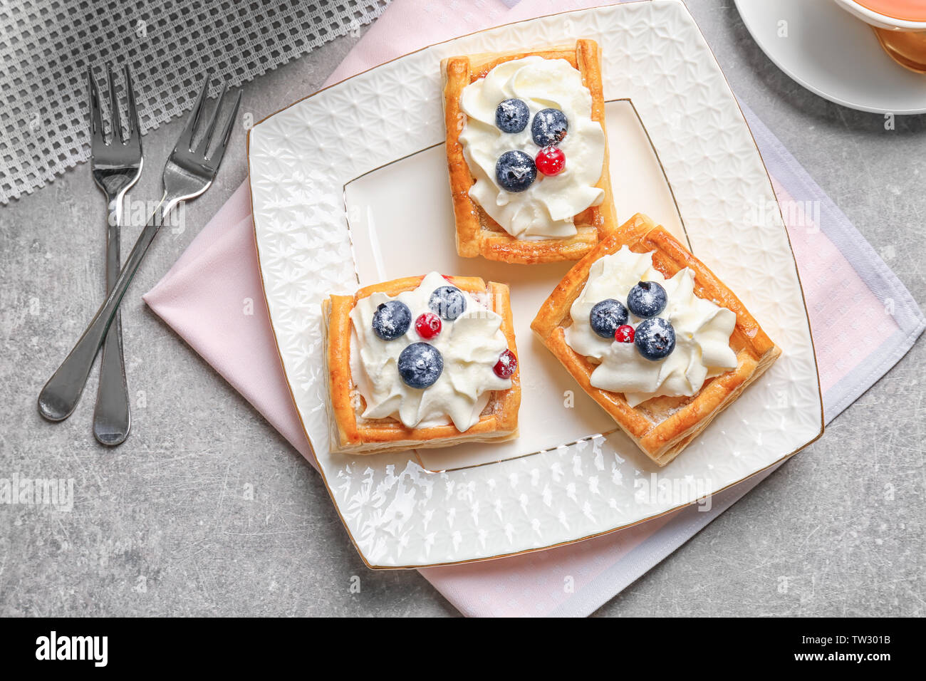 Plate with pastries and forks on grey table Stock Photo - Alamy