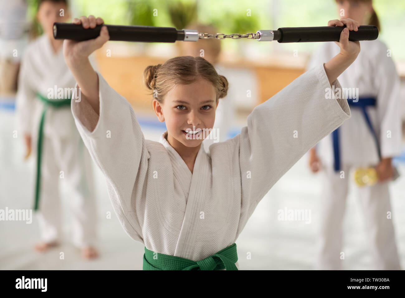 Holding nunchucks. Blonde-haired girl with hair buns holding nunchucks ...
