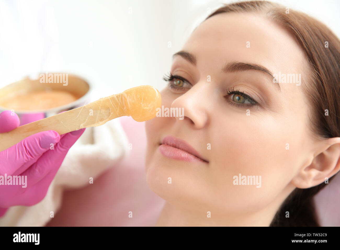 Woman having hair removal procedure on face with wax depilatory in ...