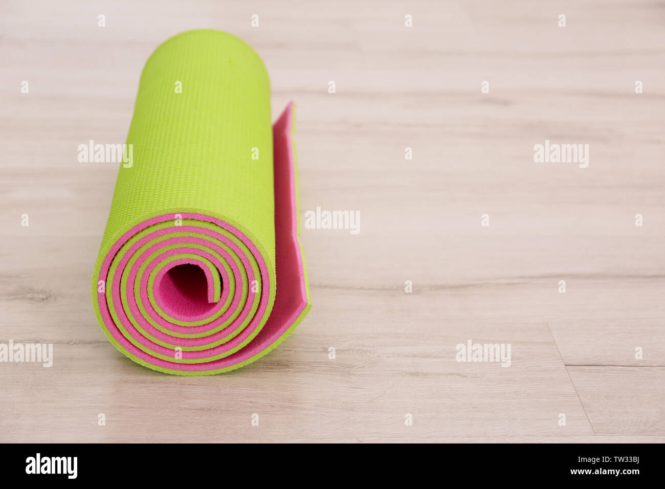 Rolled up yoga mat on wooden floor Stock Photo - Alamy