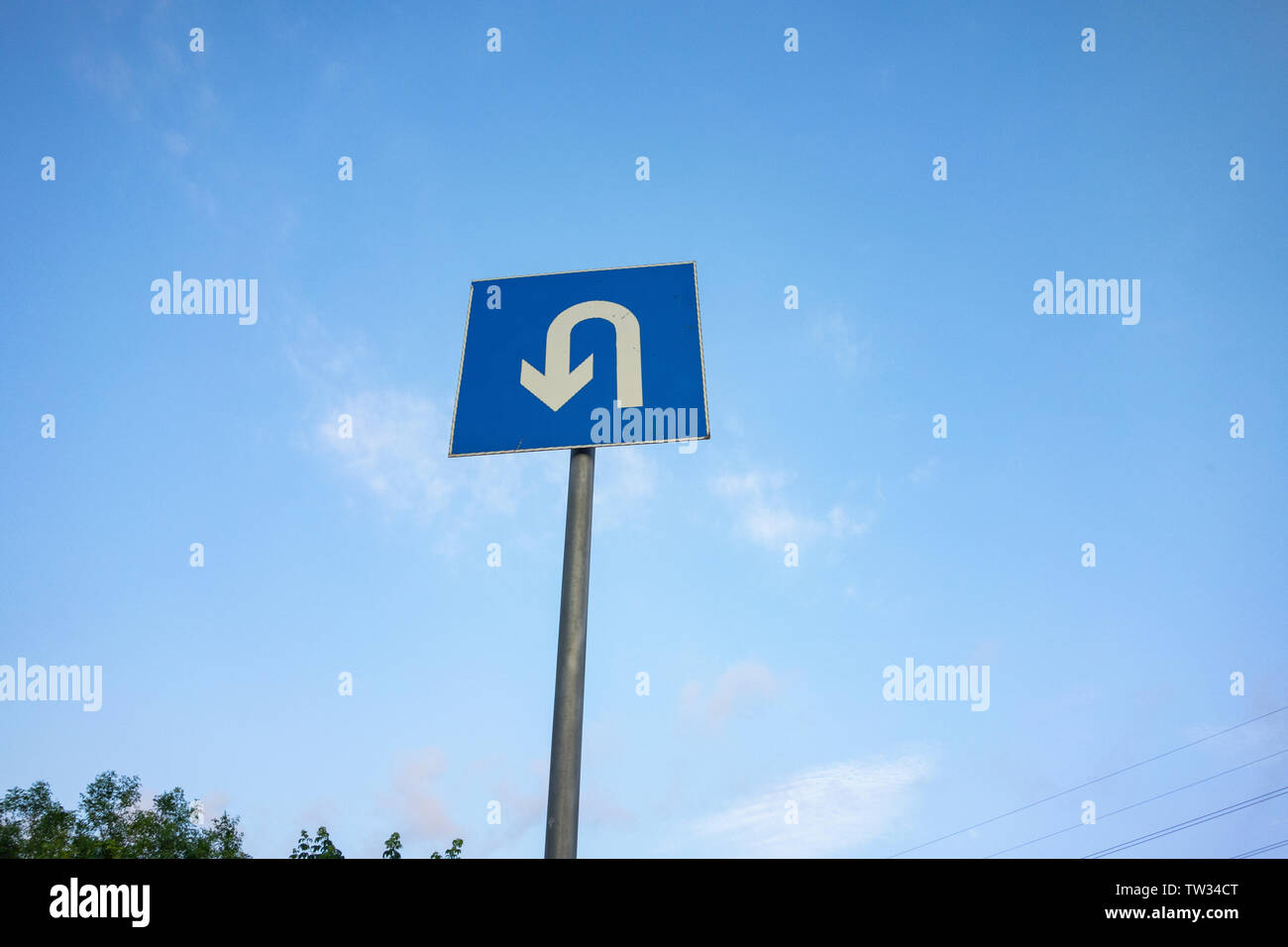 A road sign with turning instructions in the background of a blue sky ...
