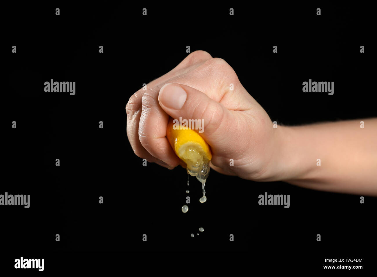 Female hand squeezing half of lemon on black background Stock Photo - Alamy