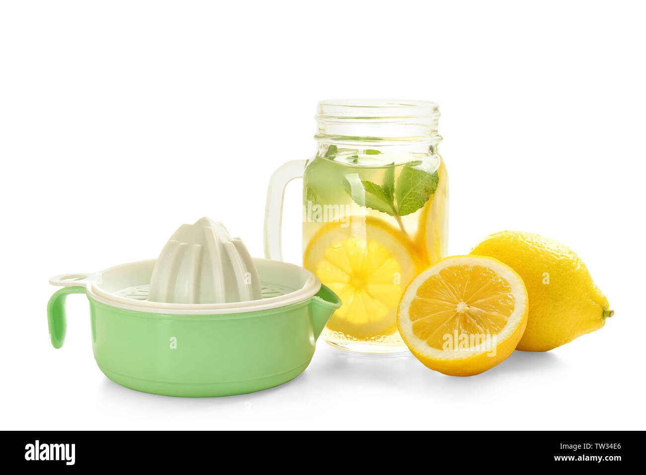 Plastic squeezer, fresh lemons and jar with lemonade on white ...