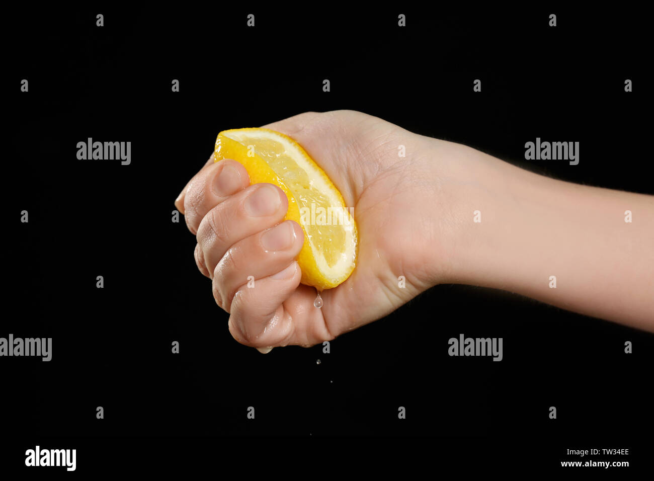 Female hand squeezing half of lemon on black background Stock Photo - Alamy