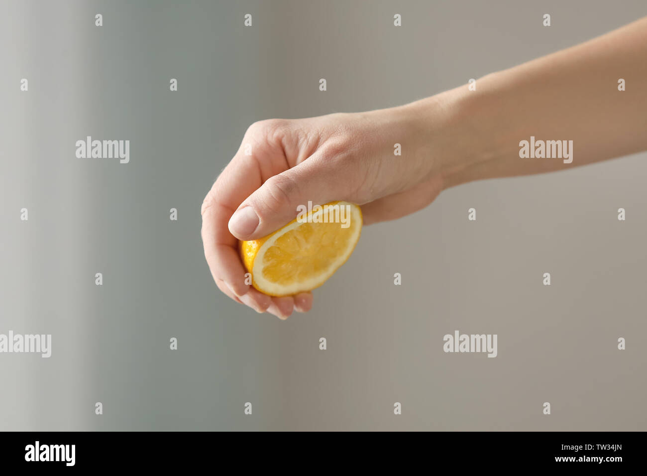 Female hand holding half of lemon on blurred background Stock Photo - Alamy