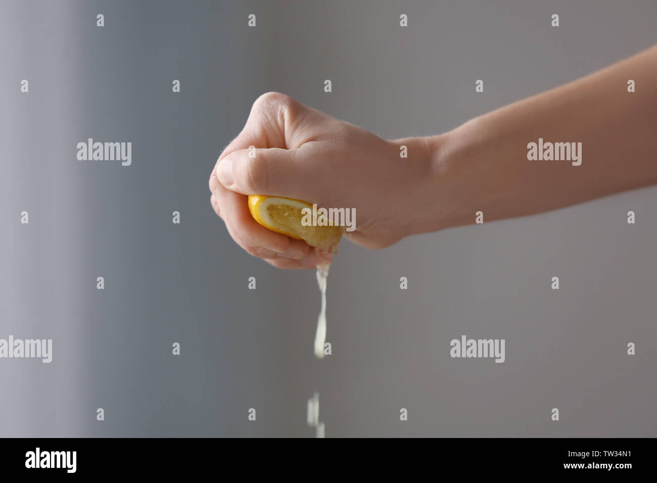 Female hand squeezing half of lemon on blurred background Stock Photo ...