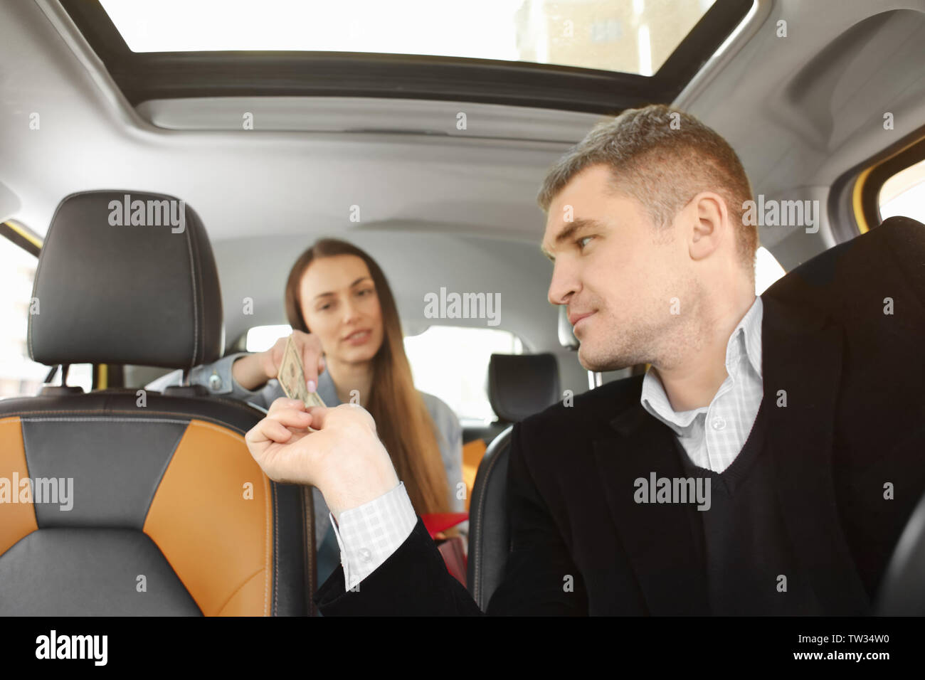 Male taxi driver receiving payment from female passenger Stock Photo ...