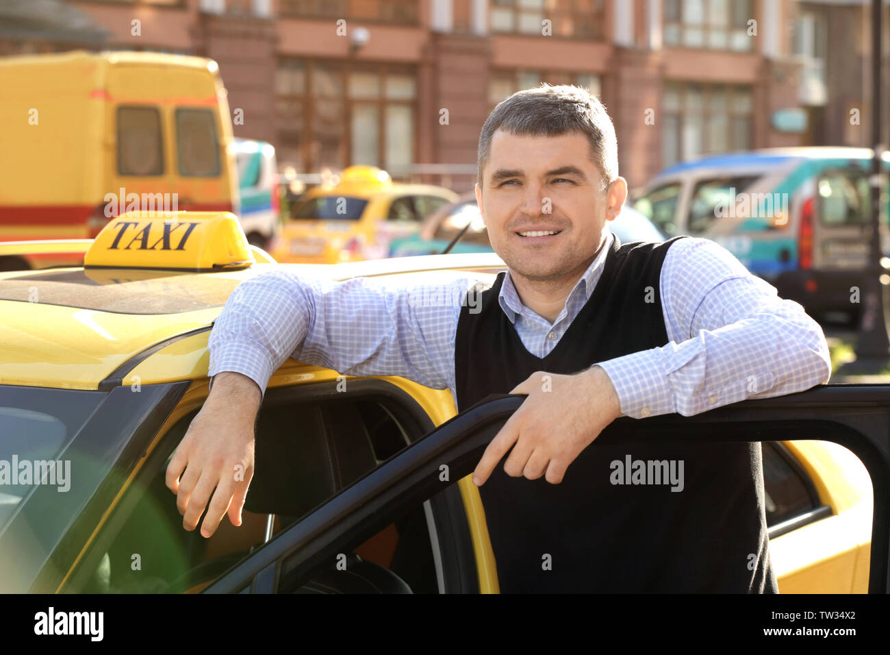 Handsome taxi driver standing near car with opened door on street Stock ...