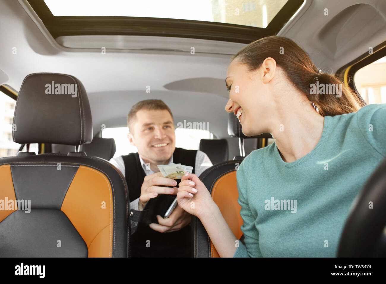 Female taxi driver receiving payment from male passenger in car Stock ...