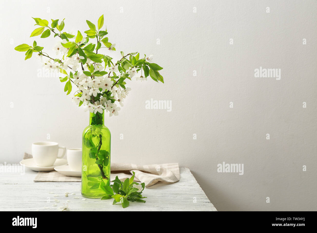 Branches of blooming tree flowers and leaves in glass vase on wooden ...