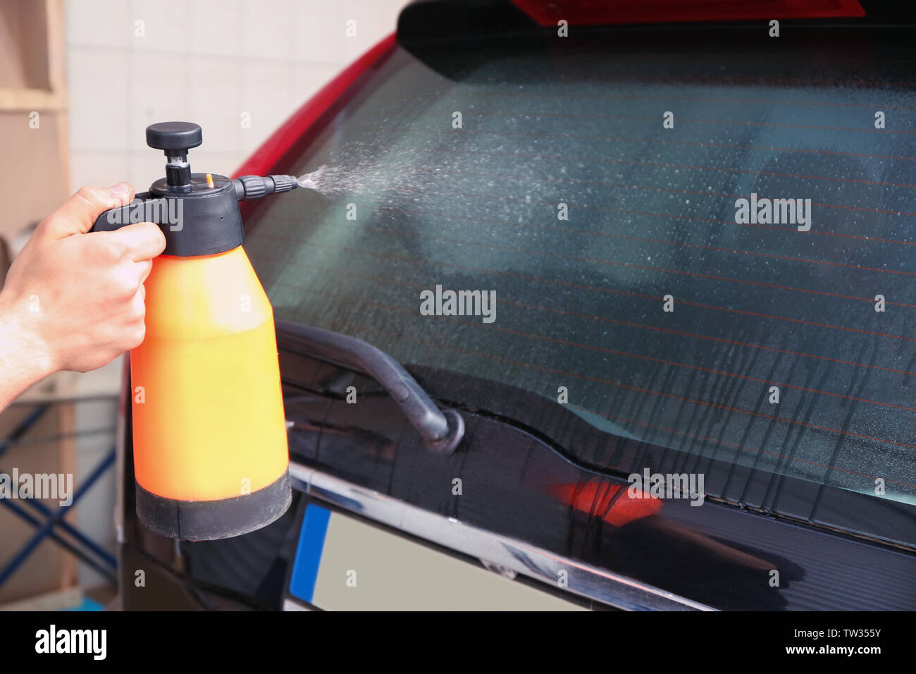 Worker spraying water onto car window Stock Photo - Alamy