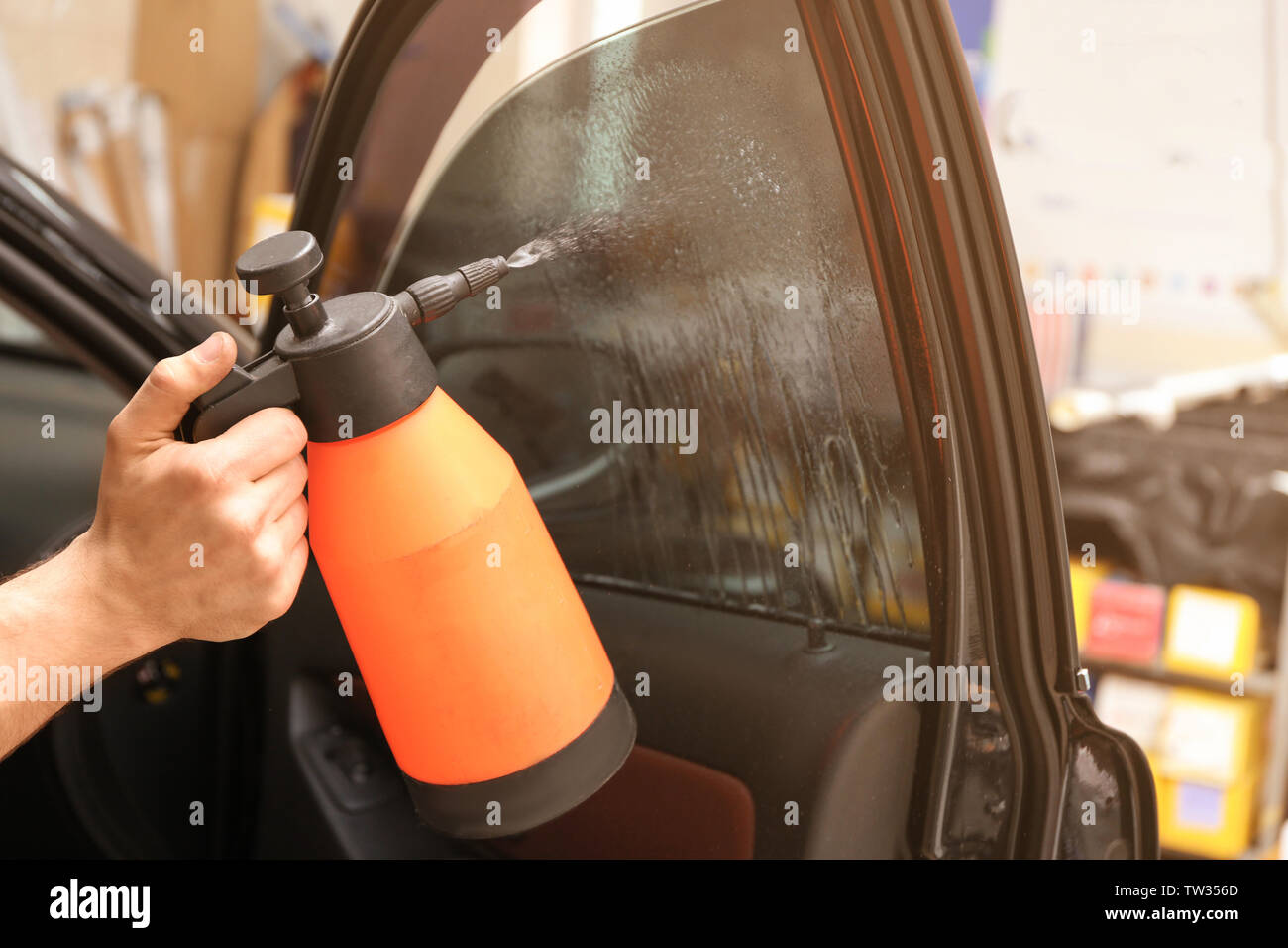 Worker spraying water onto car window Stock Photo - Alamy