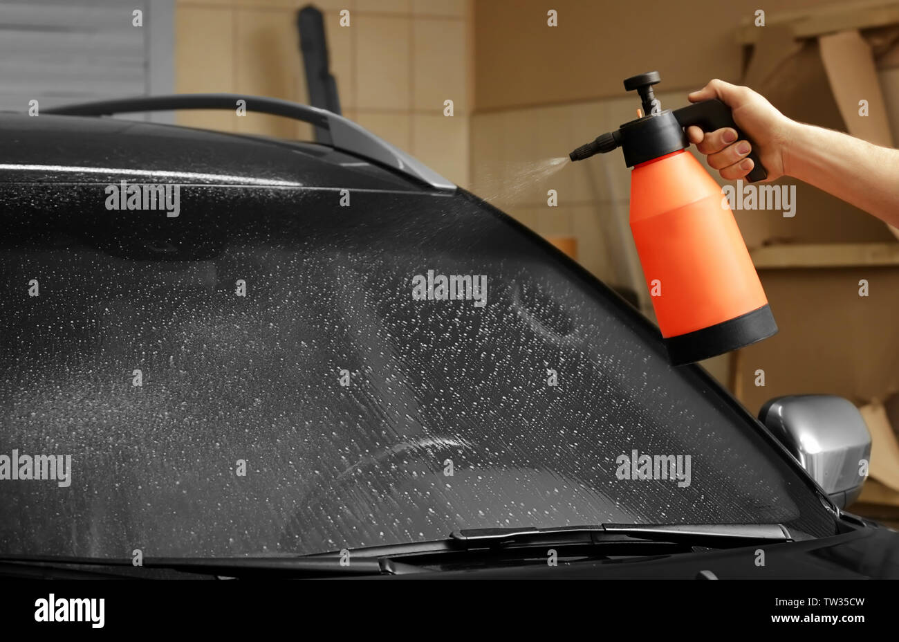Worker spraying water onto car window prior to tinting Stock Photo - Alamy