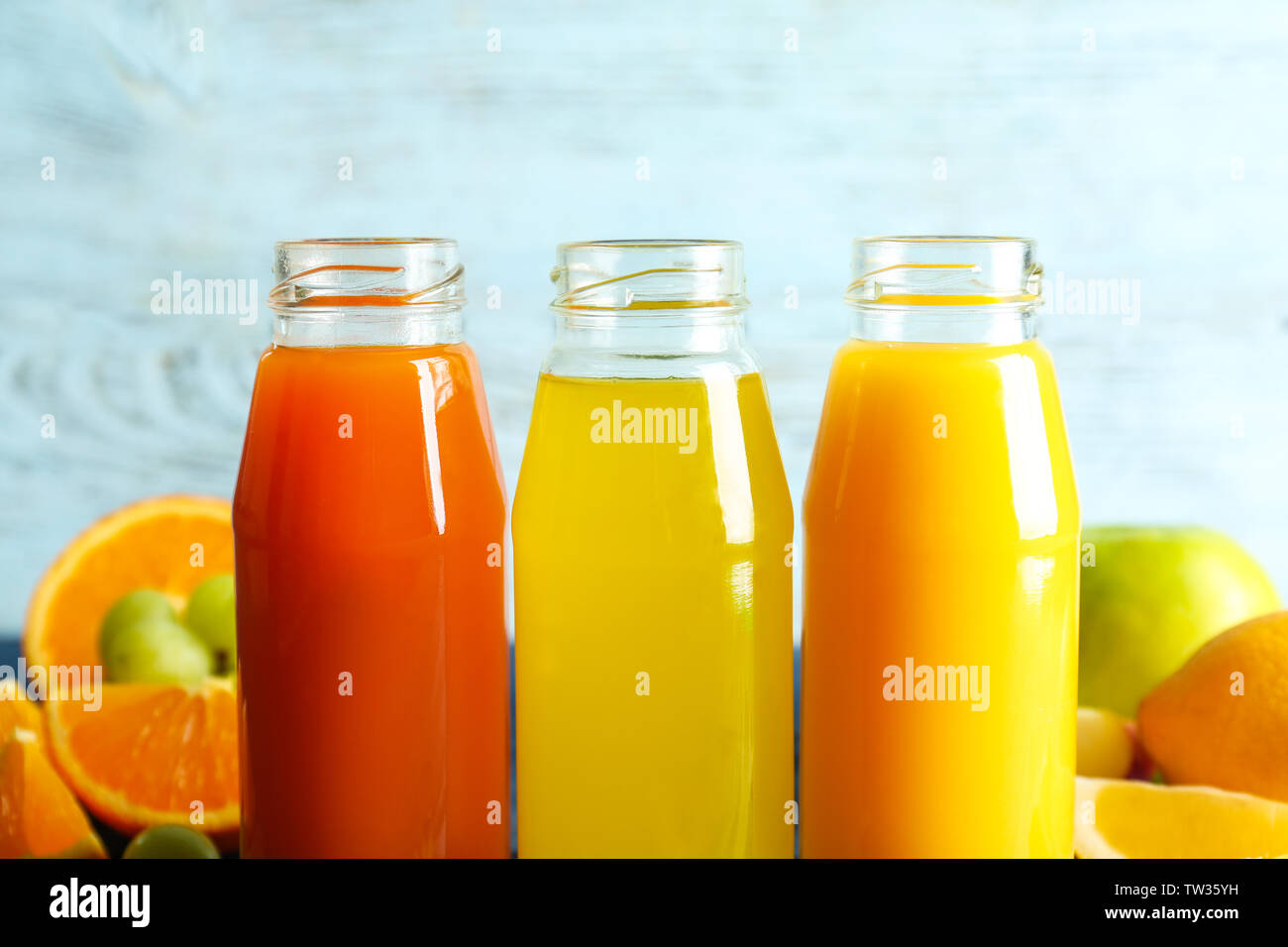 Delicious juices in bottles and fruits on light background Stock Photo ...