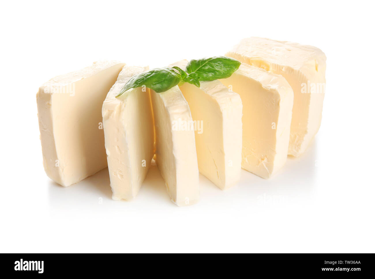 Delicious butter pieces with basil leaves on white background, closeup ...