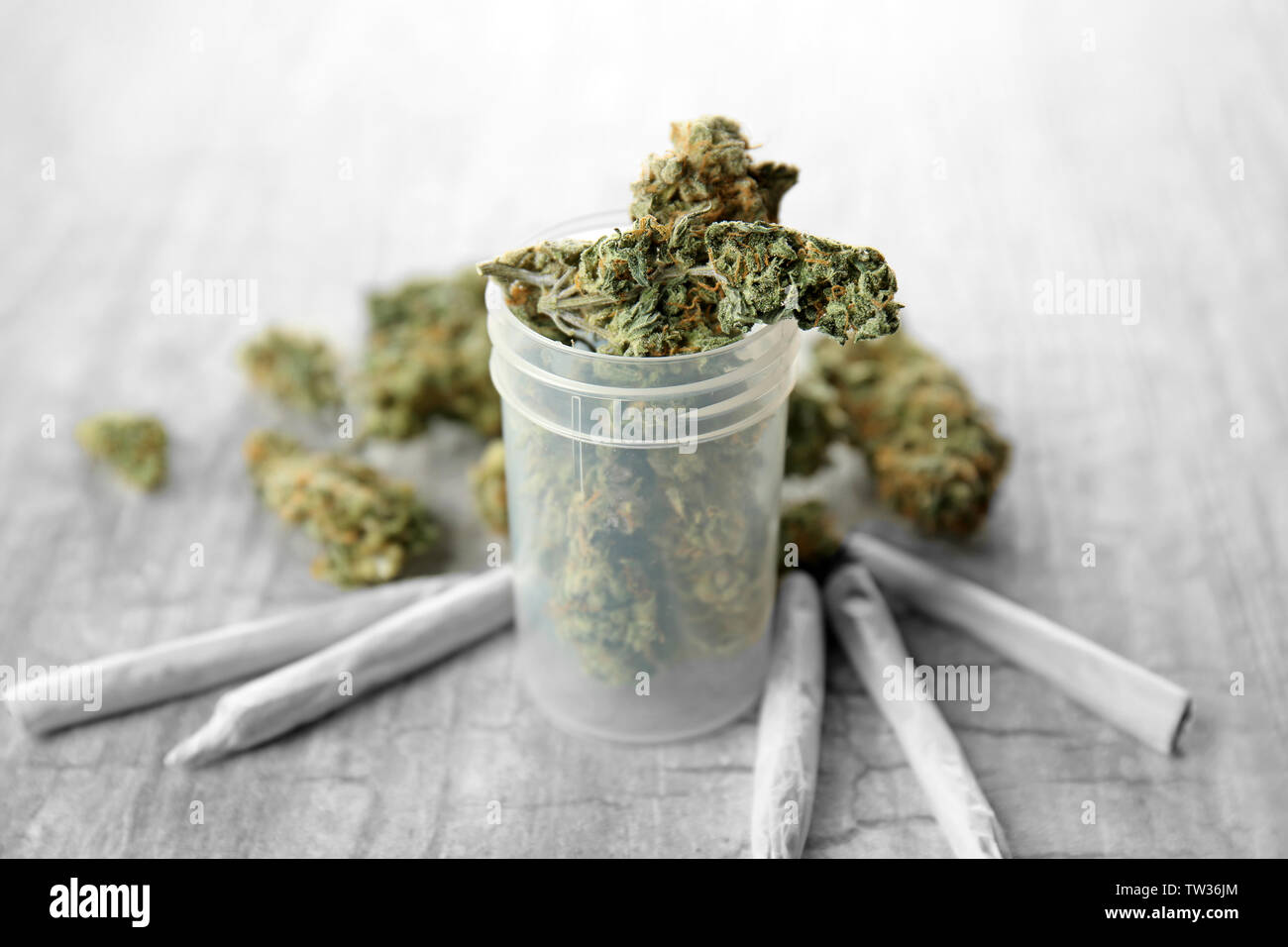 Weed buds in plastic container with cigarettes on grey background Stock ...