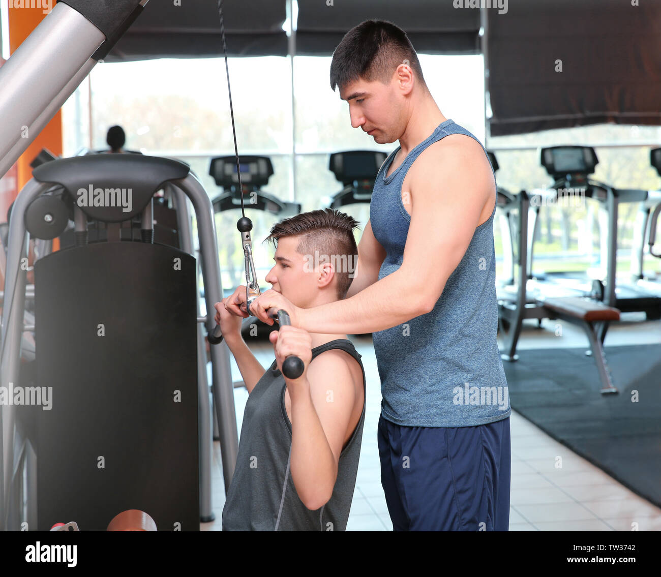 Dad and son training with cable-pull machine in modern gym Stock Photo ...