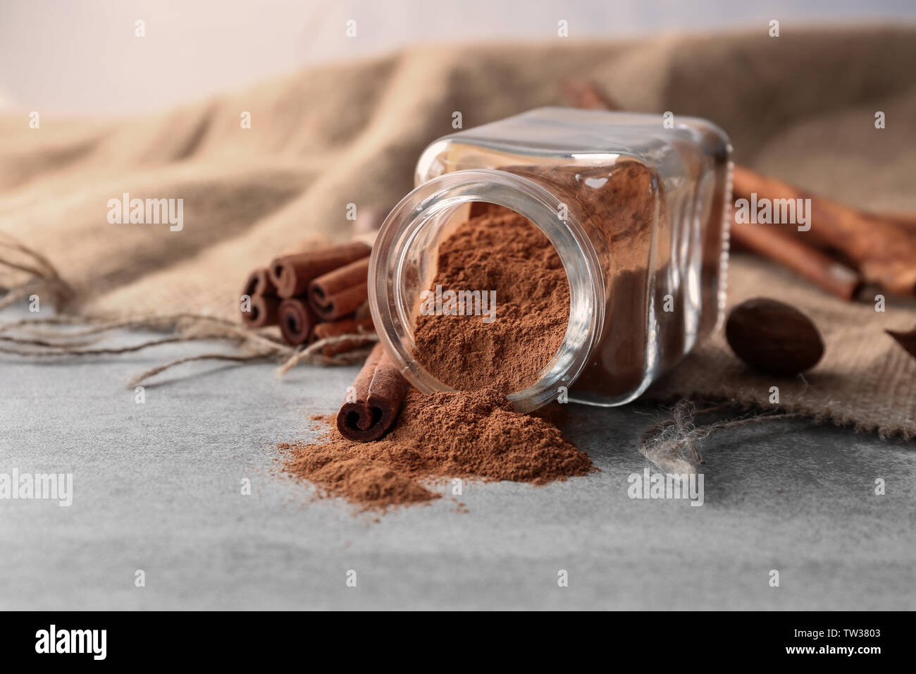 Glass jar with powdered cinnamon and sticks on light table Stock Photo ...