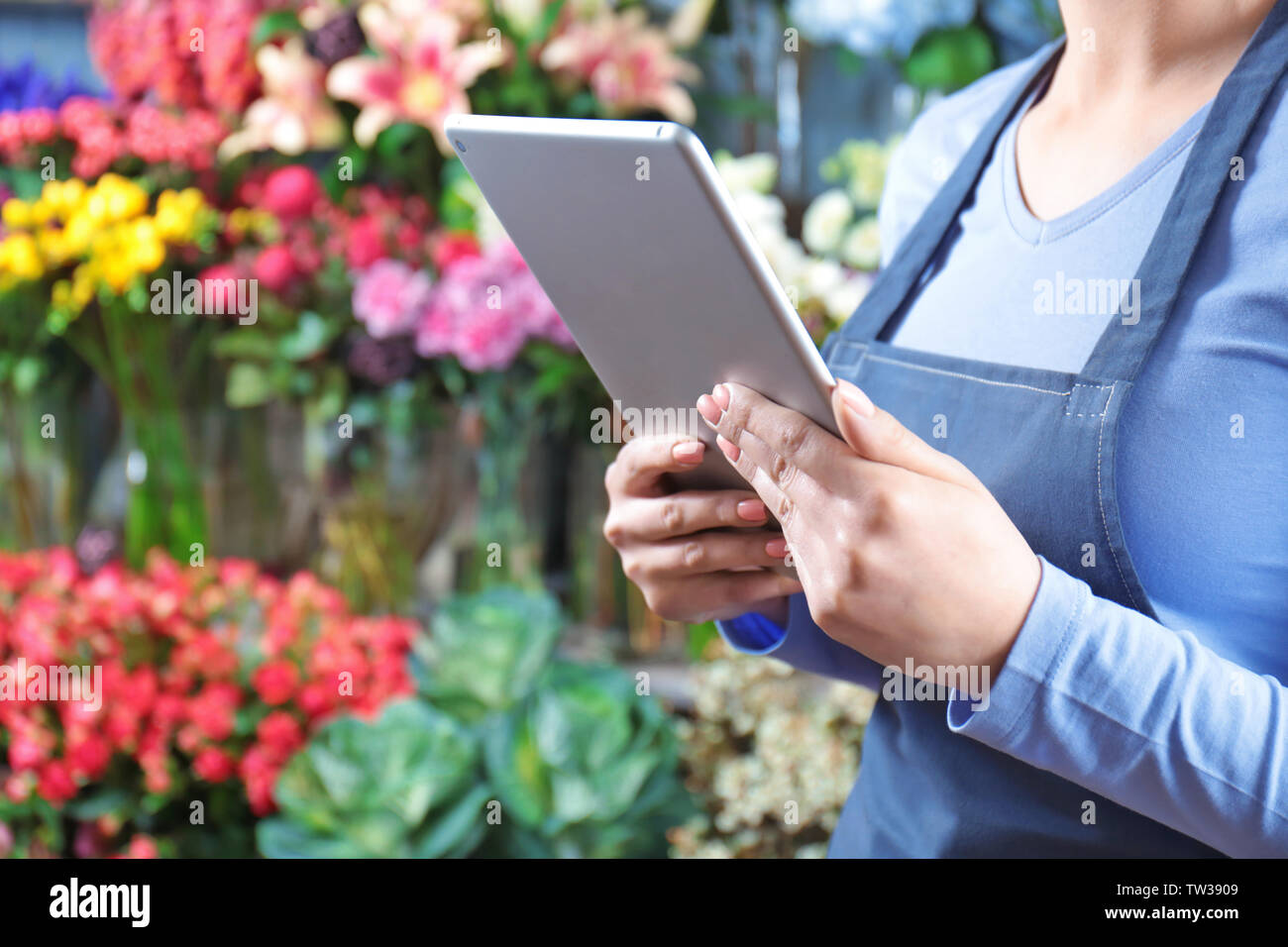 Beautiful female florist with tablet in flower shop Stock Photo - Alamy