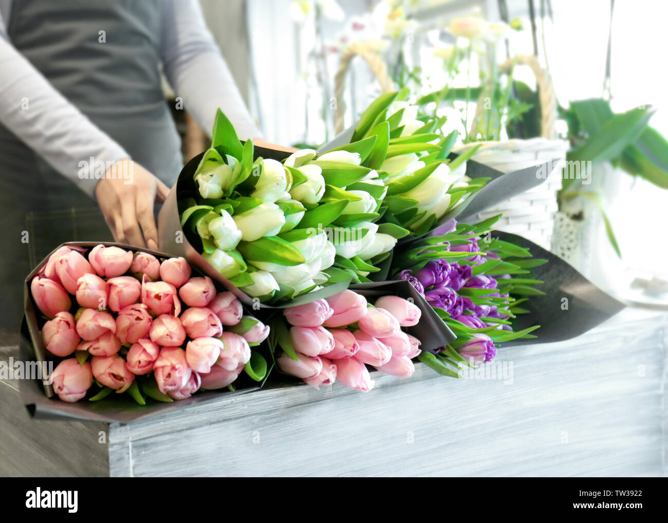 Female florist standing near counter with beautiful bouquets in flower ...