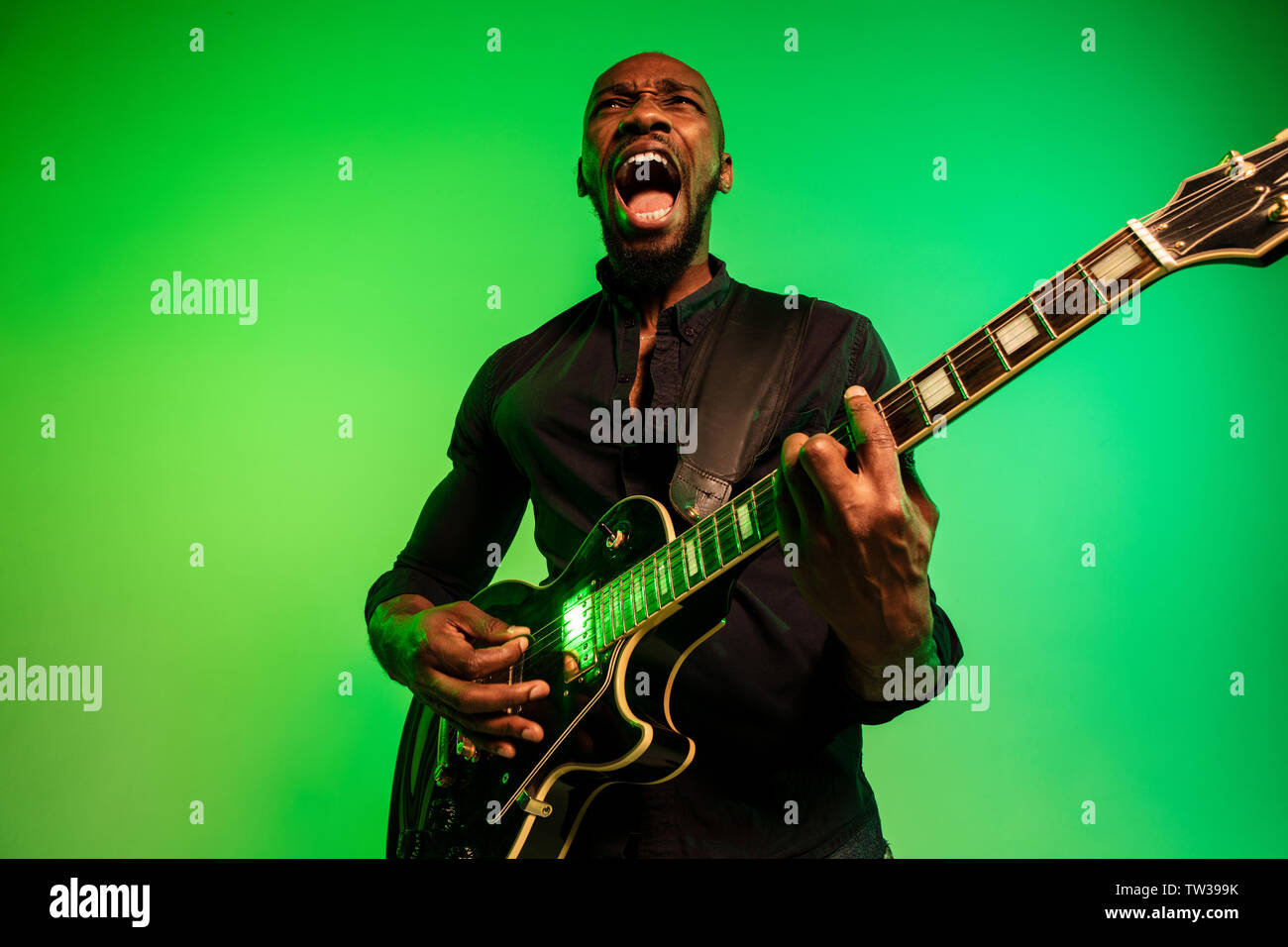 Young african-american musician playing the guitar like a rockstar on ...