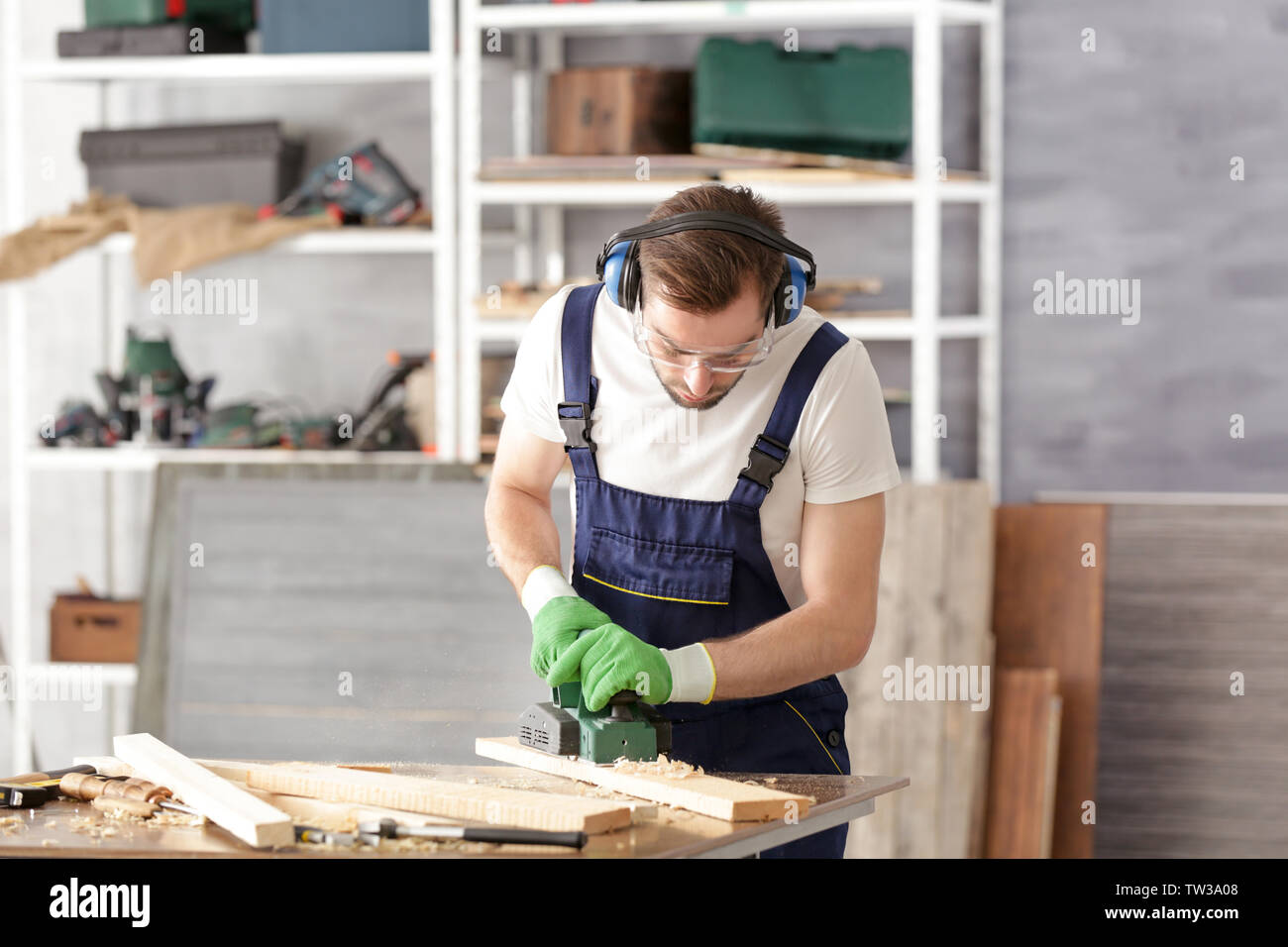 Carpenter planing timber in light workshop Stock Photo - Alamy